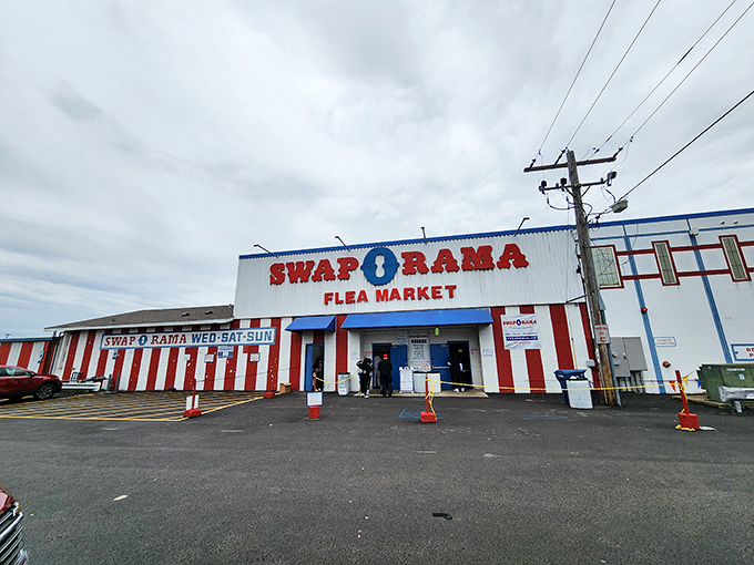 The red and white striped facade of Swap-O-Rama stands like a carnival of commerce, beckoning bargain hunters with promises of treasures within.