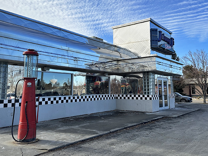 The gleaming chrome exterior of Johnny J's Diner shines like a beacon for hungry travelers, complete with vintage gas pump nostalgia.