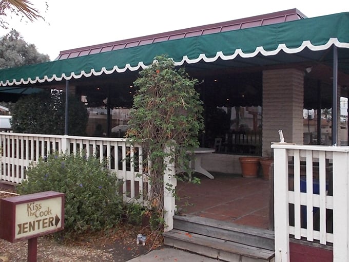A welcoming entrance that practically whispers, "Come on in and loosen your belt." The green awning and white fence create that perfect neighborhood spot vibe.