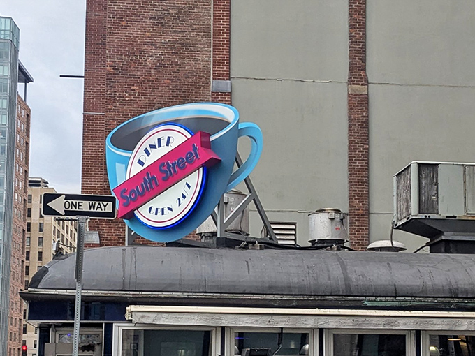 South Street Diner's unmistakable neon coffee cup sign glows against brick buildings, promising 24-hour comfort in downtown Boston.