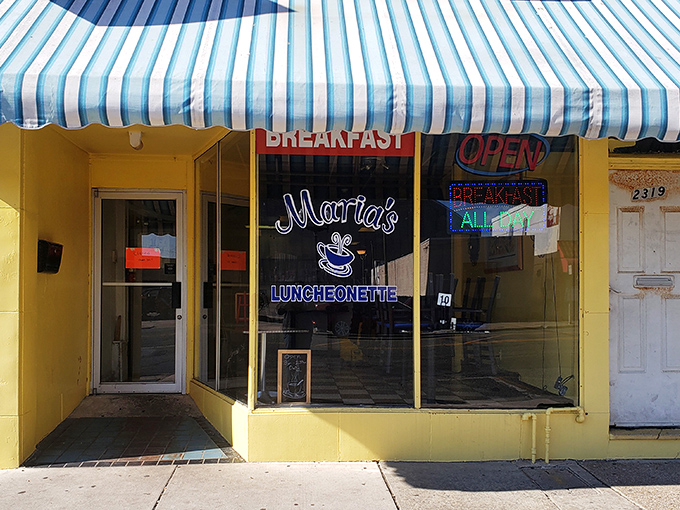 The sunny yellow exterior of Maria's Luncheonette beckons like a breakfast lighthouse amid Atlantic City's urban landscape. That blue-striped awning promises comfort food ahead.