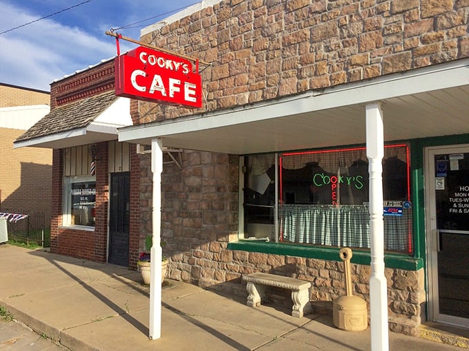 The iconic red Cooky's Cafe sign against rustic stone promises comfort food paradise in Golden City&mdash;a beacon for hungry travelers since 1942.