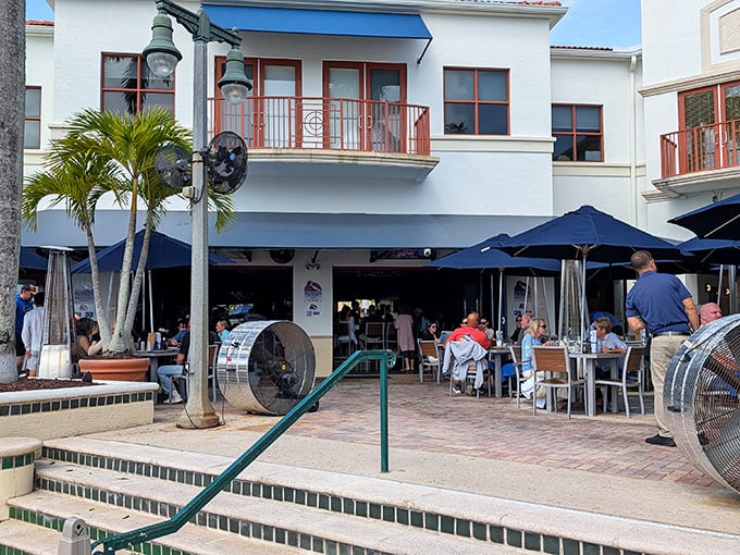 The unassuming exterior of Dive Bar Restaurant hides a culinary treasure. Blue umbrellas and palm trees hint at the Florida waterfront experience awaiting inside.