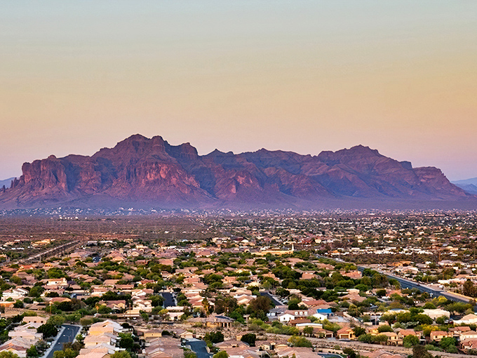 The iconic Superstition Mountains cast their purple shadow over Mesa at sunset, where affordable desert living meets breathtaking natural beauty &ndash; no filter needed for this daily Arizona masterpiece.
