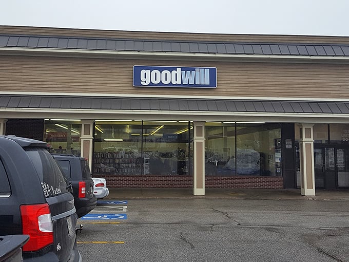 The iconic blue Goodwill sign beckons like a lighthouse for bargain hunters, promising treasures within that someone else mysteriously decided they could live without.