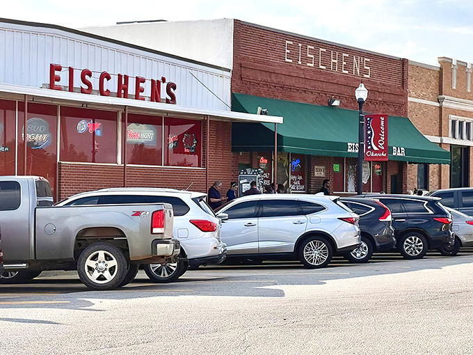 The unassuming exterior of Eischen's Bar stands like a culinary lighthouse in Okarche, beckoning hungry travelers with its iconic red signage.