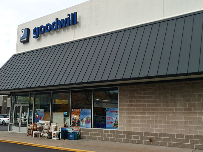 The blue Goodwill sign beckons like a lighthouse for bargain hunters. This unassuming exterior houses treasures waiting to be discovered.