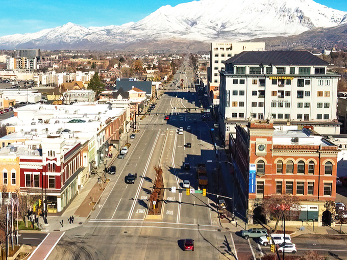 Downtown Provo stretches toward snow-capped mountains like a postcard come to life, where historic brick buildings stand shoulder-to-shoulder with modern architecture beneath Utah's impossibly blue sky.