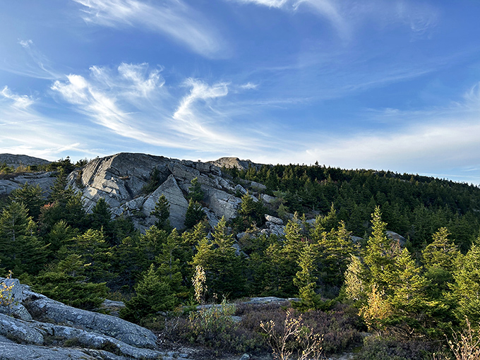 Tiny hikers dot the summit's bare rock face, demonstrating the mountain's popularity and the rewarding panoramic views awaiting climbers.