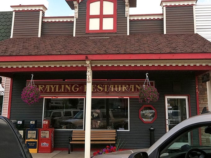Small-town charm in full display – the distinctive red-trimmed facade and hanging flower baskets create that "come on in" feeling before you even reach the door.