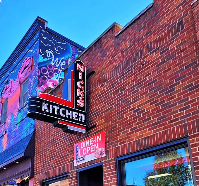 The iconic neon sign of Nick's Kitchen glows against Huntington's brick facade like a beacon for hungry travelers seeking tenderloin nirvana.