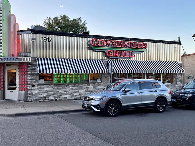 The neon-lit facade of Convention Grill stands like a time portal to the 1950s, beckoning hungry travelers with its classic striped awnings and stone exterior.