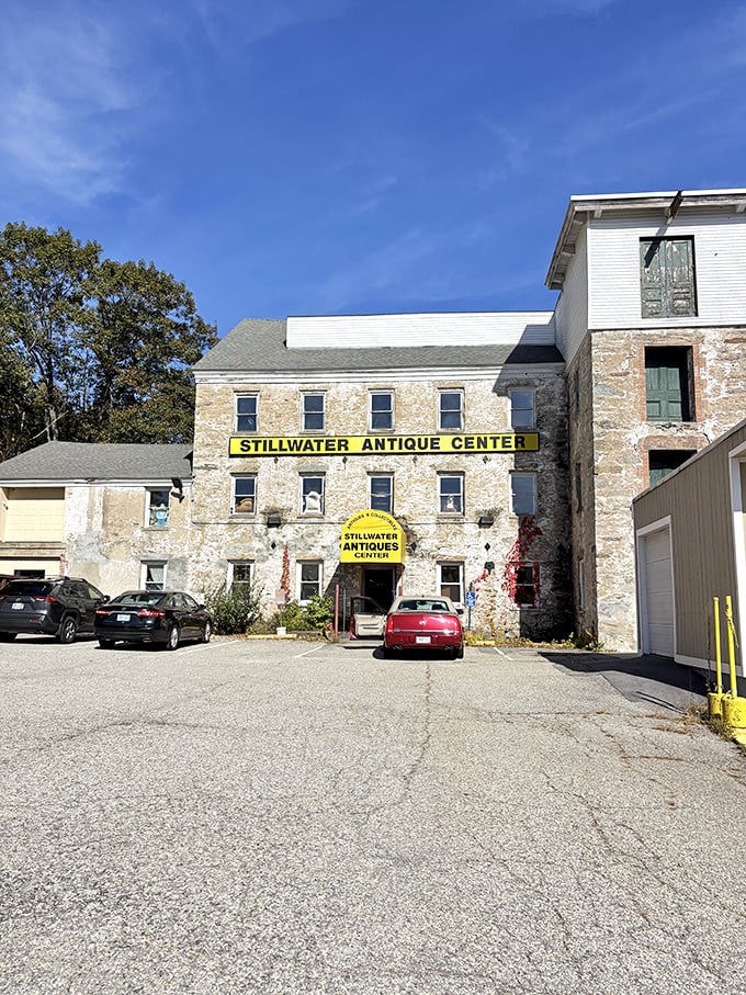 The historic stone mill building housing Stillwater Antique Center stands proudly against a blue Rhode Island sky, its weathered facade telling stories before you even step inside.