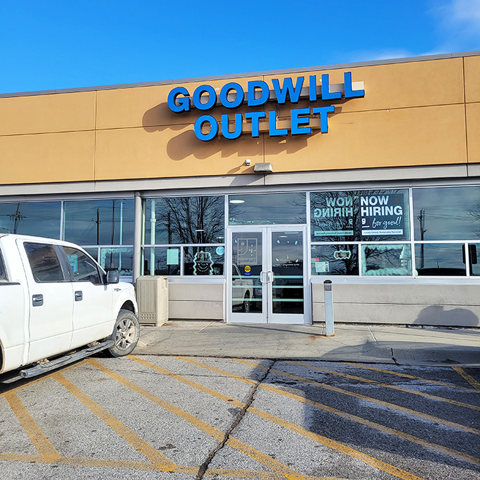 The Goodwill Outlet sign shines bright under the blue sky. Time for great finds! A white pickup truck is parked nearby.