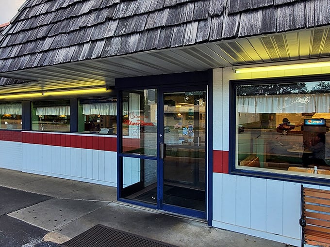That iconic blue sign beckons like a lighthouse for hungry travelers. The weathered shingles and red trim whisper stories of decades serving Highland's best burgers.