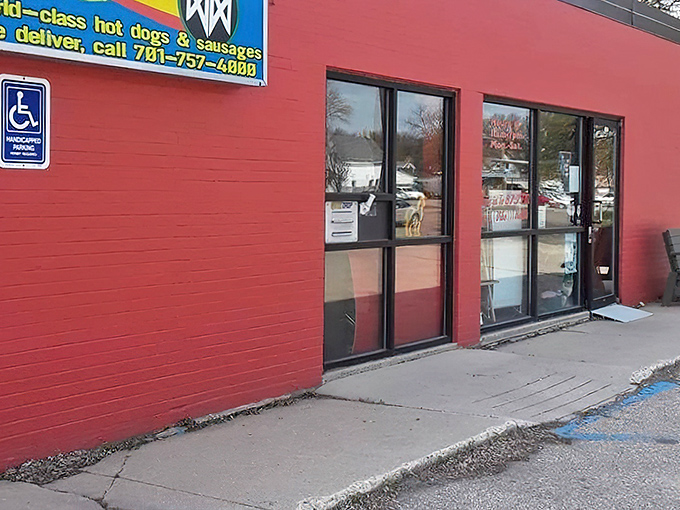 The bright red exterior of DogMahal DogHaus beckons like a culinary lighthouse in Grand Forks, promising affordable delights within its unassuming walls.