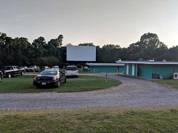 The iconic turquoise concession building and white screen await as dusk settles over the Kenda Drive-In, where memories are made under Arkansas stars.