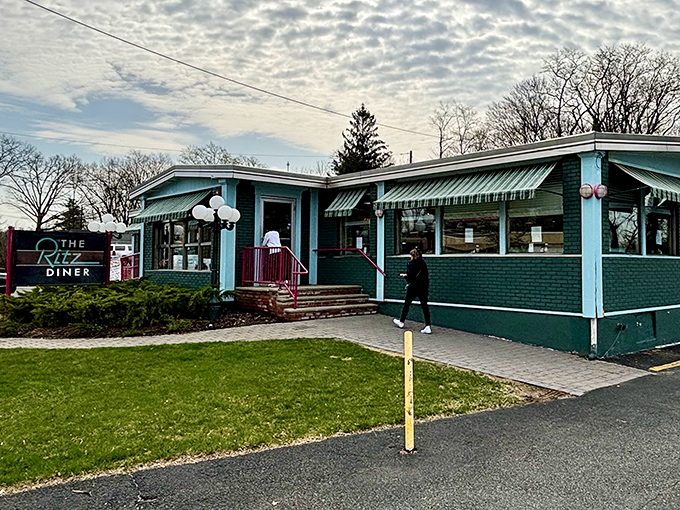 The teal and pink exterior of the Ritz Diner stands like a time capsule from a more affordable era, welcoming hungry patrons with retro charm.
