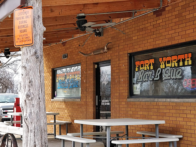 Fort Worth Bar-B-Que's rustic brick exterior welcomes hungry patrons with outdoor seating and western charm.