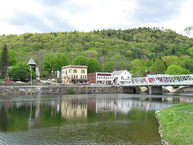 The Iron Bridge creates a perfect frame for Shelburne Falls' riverside buildings, reflecting in waters so calm they could be meditating.
