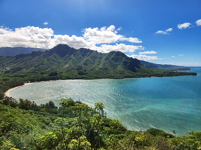 The windward coast reveals its quiet majesty, where lush vegetation frames Kahana's pristine beach and protective mountain sentinels.