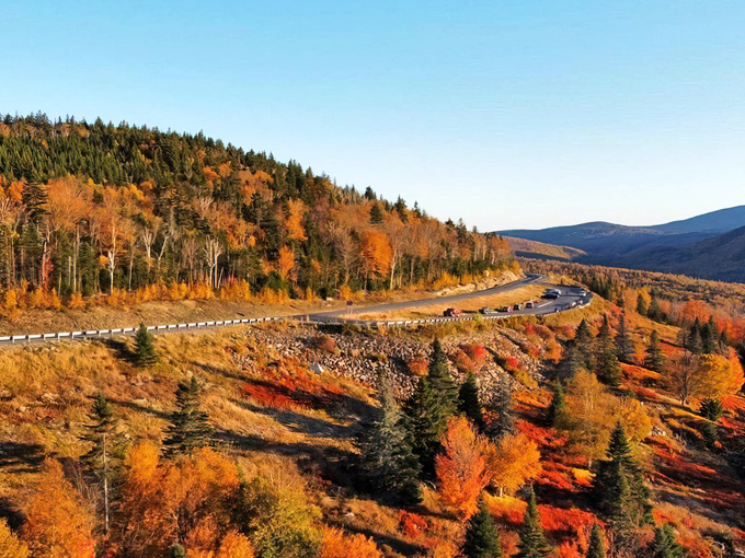 Autumn's fiery palette transforms the winding Rangeley Lakes Scenic Byway into a golden ribbon through Maine's mountains.