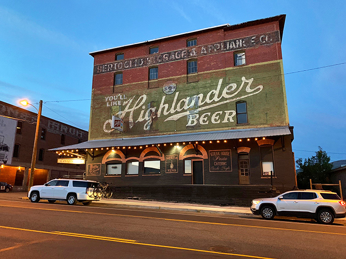 Vintage Highlander Beer advertisement adorns Casagranda's historic building, illuminated at dusk&mdash;a perfect blend of Montana's brewing and dining heritage.