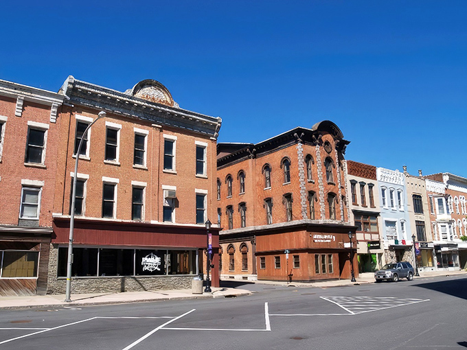 Historic brick buildings stand sentinel on Amsterdam's Main Street, where your wallet breathes easier and parking spots don't require advanced strategic planning.