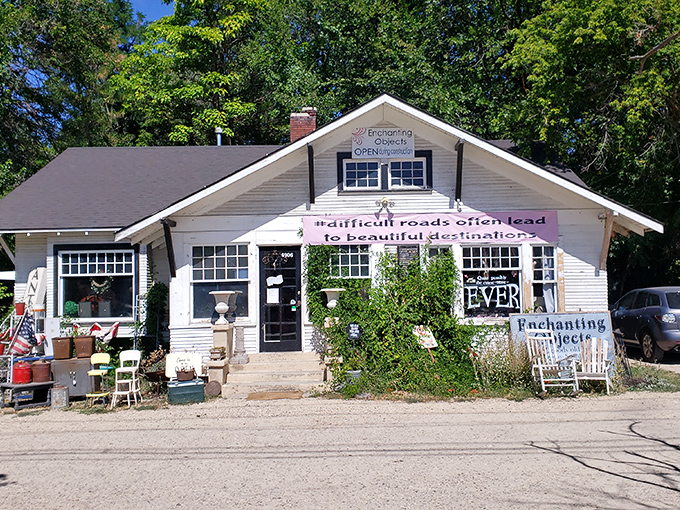 The charming white cottage exterior of Enchanting Objects beckons with its philosophical banner and treasures already spilling onto the porch.