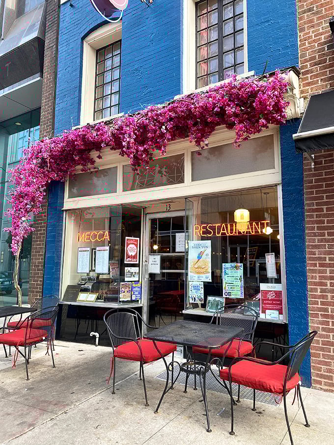 The vibrant blue exterior of Mecca Restaurant with cascading pink flowers creates the kind of entrance that says, "Yes, something delicious is definitely happening inside."