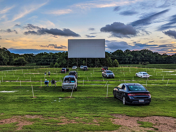 As twilight descends, cars gather like fireflies around the glowing screen. Movie magic in its purest form awaits under an Alabama sky.