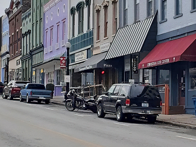 Historic storefronts line Harrodsburg's Main Street, where modern vehicles park alongside charming small-town businesses.