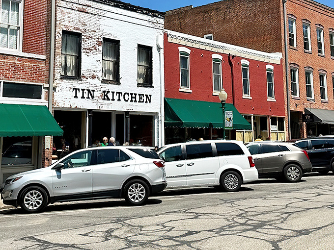 The Tin Kitchen stands proudly on Weston's Main Street, its weathered brick facade telling stories of bygone eras while modern cars hint at its enduring popularity.