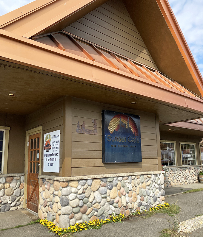 A closer look at Sunset Cafe's rustic exterior reveals thoughtful details&mdash;river rock foundation, cheerful yellow flowers, and that iconic sign beckoning hungry travelers.