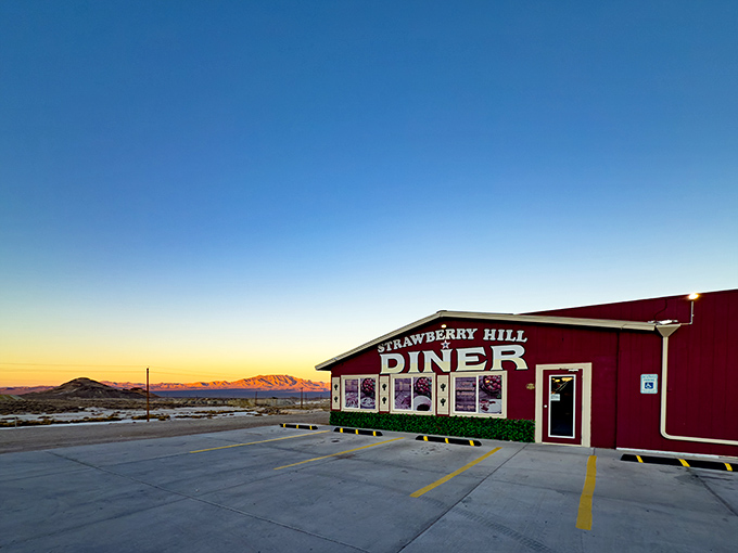 The crimson beacon of Strawberry Hill Diner stands defiantly against the vast Nevada desert, promising culinary salvation to weary travelers as the sun dips behind distant mountains.