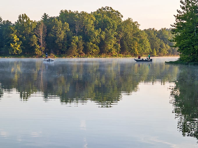 Morning mist rises off Kincaid Lake as fishing boats glide through waters so still they mirror the sky perfectly.