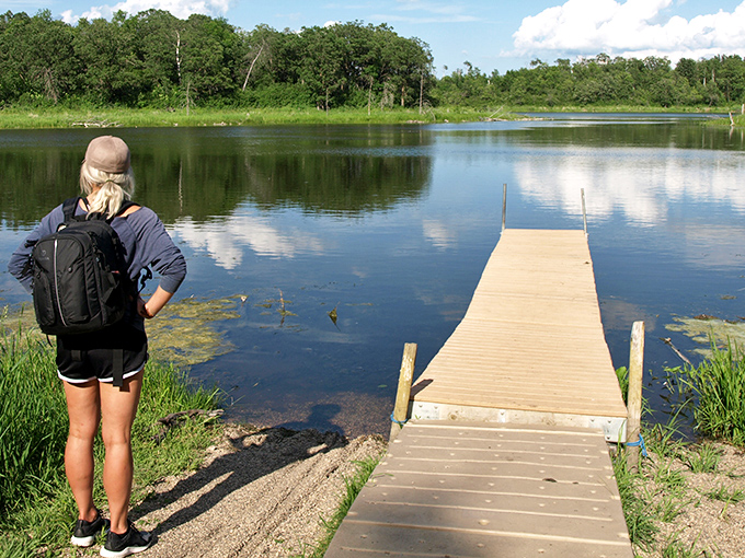 A wooden dock stretches into the tranquil waters of Lake Metigoshe, inviting visitors to pause and contemplate nature's perfect reflection.