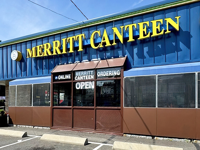 The distinctive gold lettering against vibrant blue announces Merritt Canteen's presence, a Connecticut institution that's embraced modern conveniences without sacrificing tradition.
