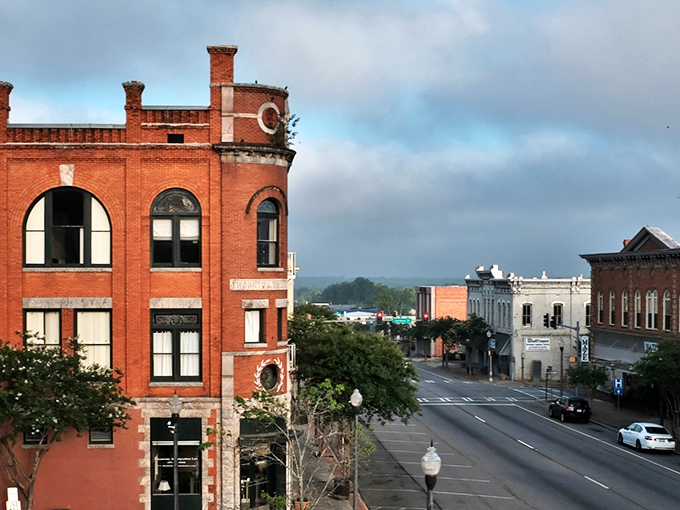 Historic brick buildings line Americus' charming downtown street under moody Georgia skies.