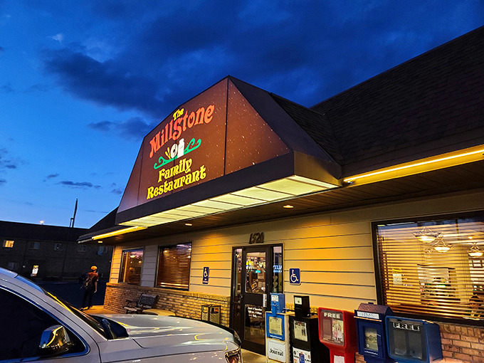 The Millstone's twilight glow beckons hungry travelers like a lighthouse for the famished. Those illuminated letters promise comfort food salvation just steps away.