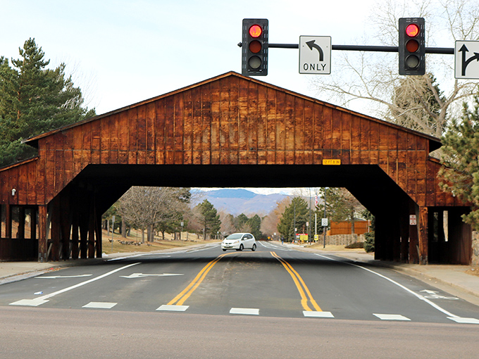 Littleton's iconic wooden bridge welcomes you like a rustic time portal, where modern traffic meets small-town charm beneath weathered beams.