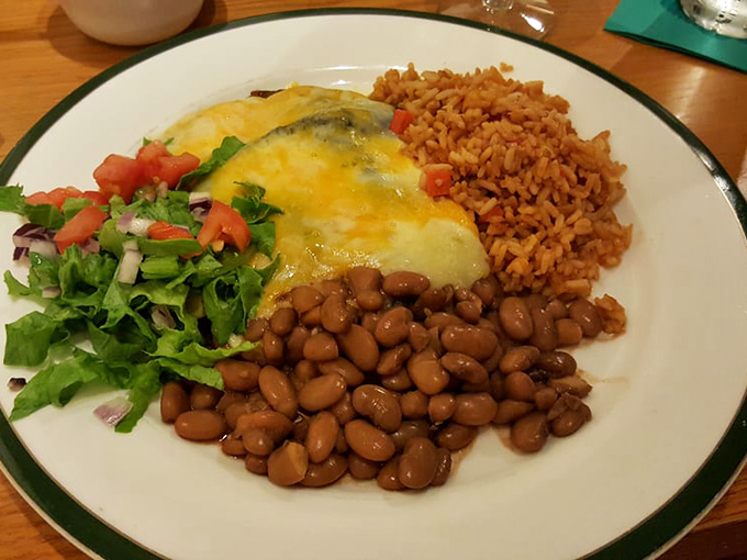 A proper New Mexican plate where the enchilada is the star, beans and rice are the supporting cast, and that green chile sauce deserves an Oscar.
