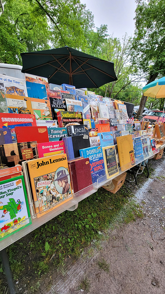 Literary treasures await beneath a green umbrella. From John Lennon biographies to vintage Southern Living, these weathered pages hold stories beyond what's printed inside.