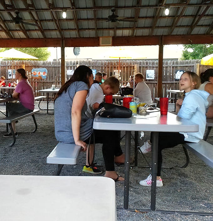 The covered outdoor seating area offers a casual, family-friendly atmosphere where BBQ brings strangers together like old friends.