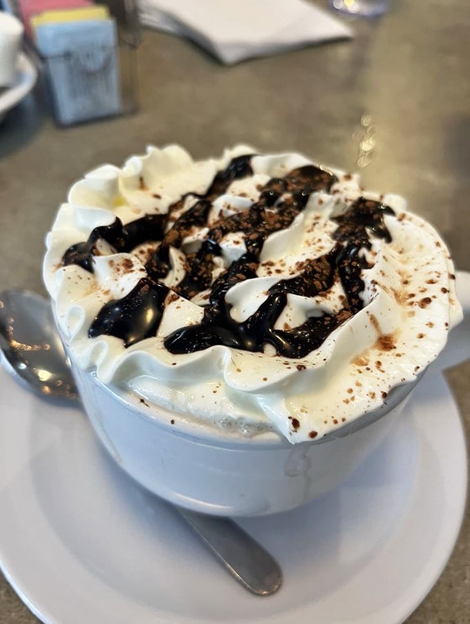 Hot chocolate that doesn't just warm your hands but hugs your soul – topped with whipped cream mountains and chocolate drizzle valleys.