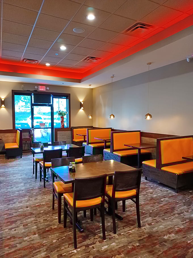 The modern dining area with its warm orange accents and pendant lighting creates an atmosphere that says, "Stay awhile, there's always room for seconds."