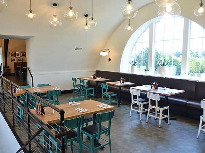 Bright turquoise chairs pop against white walls and natural light in this dining area, where the arched windows frame meals worth remembering.