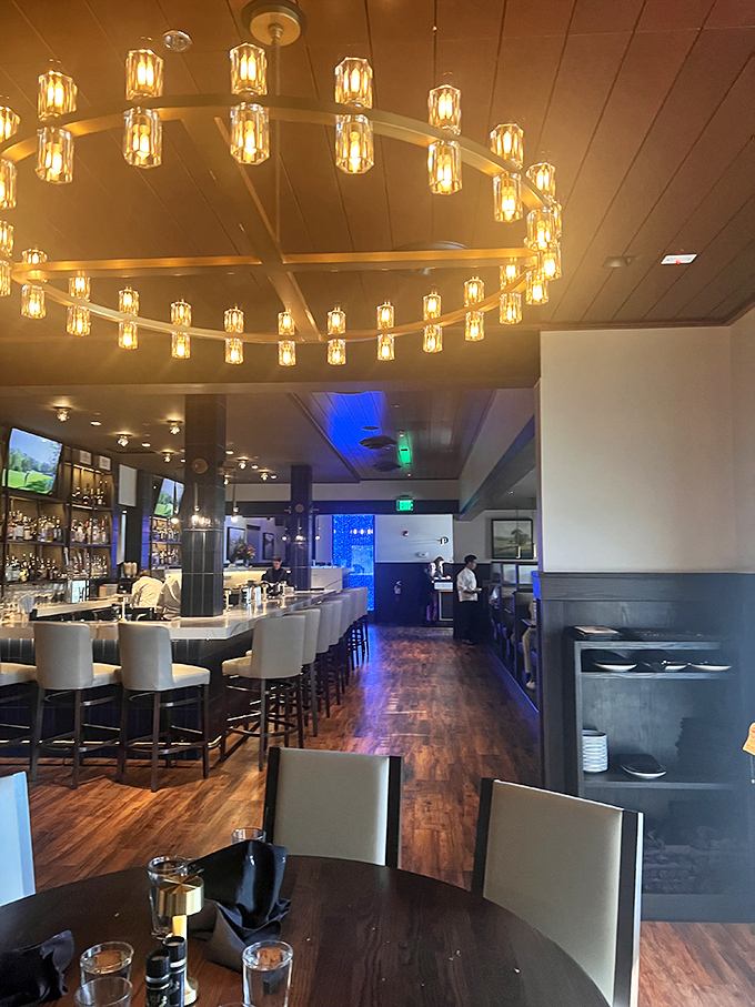 The circular chandelier casts a golden glow over the dining room, setting the stage for conversations that flow as smoothly as the wine.