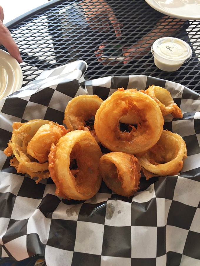 Onion rings with the perfect crunch-to-squish ratio, served in a checkered basket that screams "I'm about to make your cardiologist very concerned."