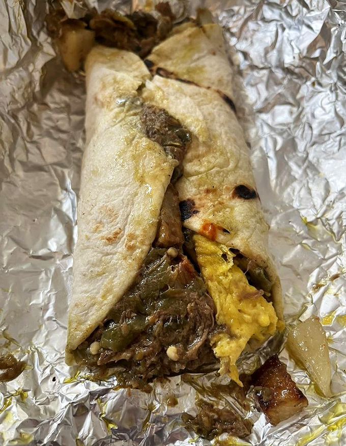 Breakfast artistry in progress. The roast beef burrito reveals its secrets: tender meat, fluffy eggs, and that essential green chile kick.